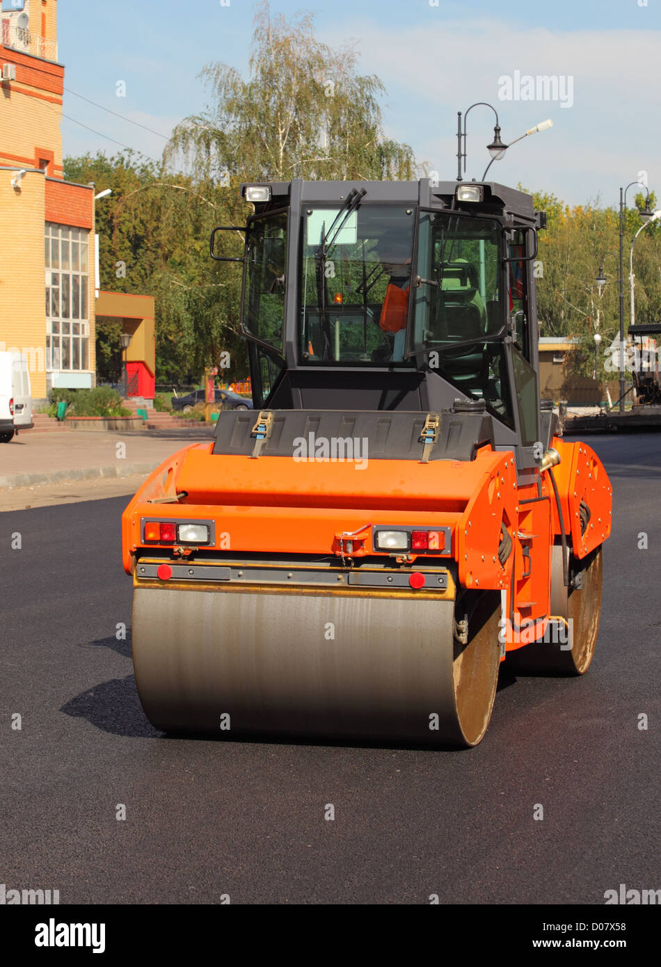 Road roller is used to place the first layer of asphalt on a city ...