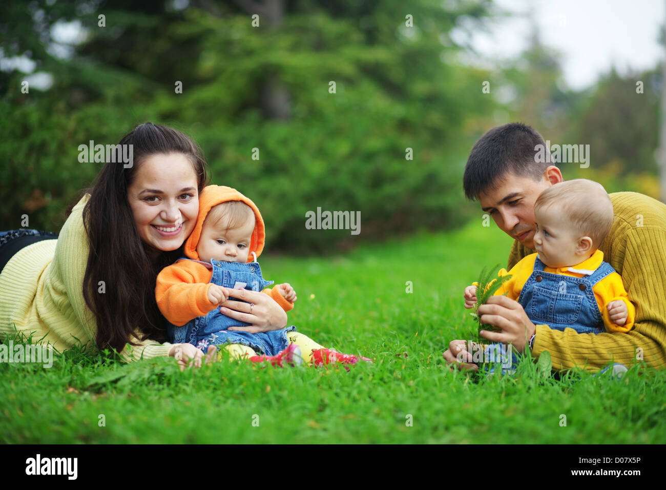 Portrait of happy young parents with their two babies twins having fun ...