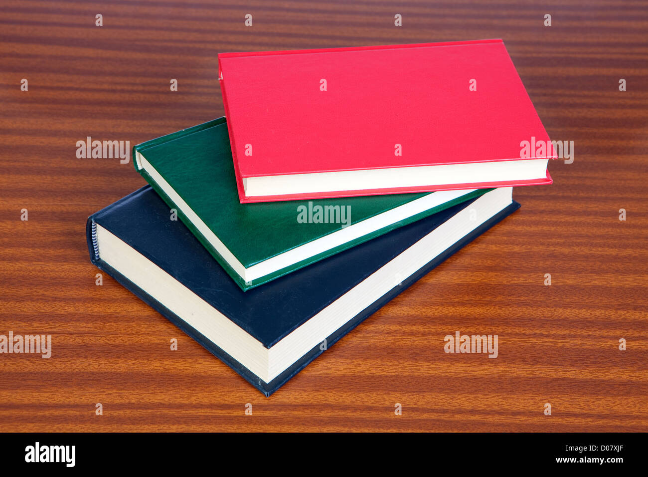 Three hardcover books on a wooden surface Stock Photo - Alamy