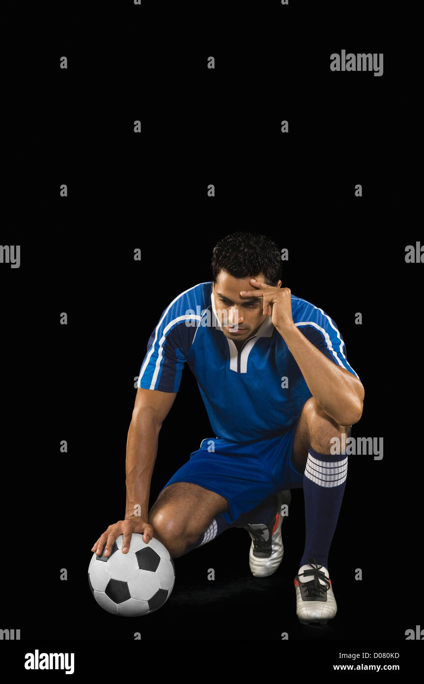 Soccer player crouching with his head in hand Stock Photo - Alamy