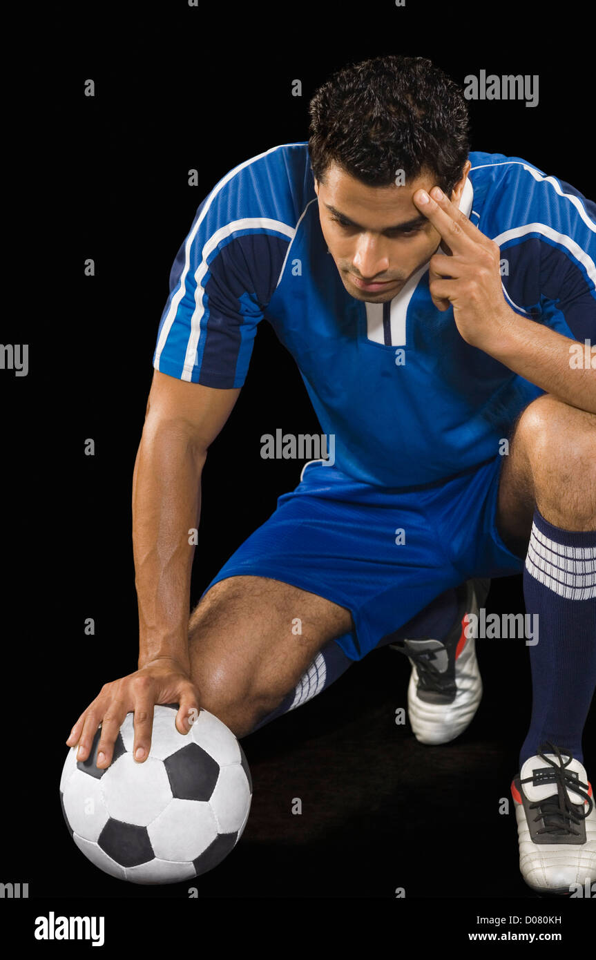 Soccer player crouching with his head in hand Stock Photo - Alamy
