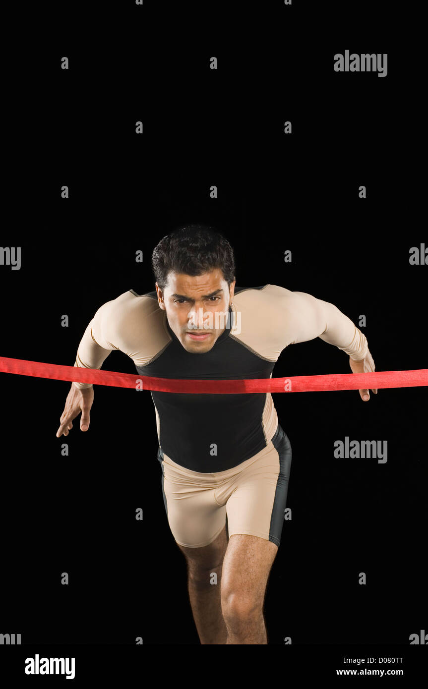 Athlete running through a finishing line Stock Photo - Alamy