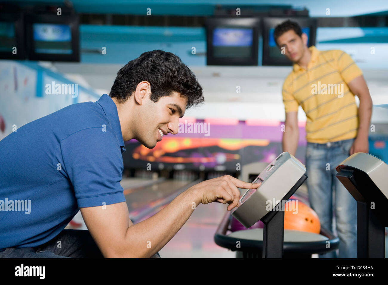 Young man operating the control panel and his friend looking at him in ...