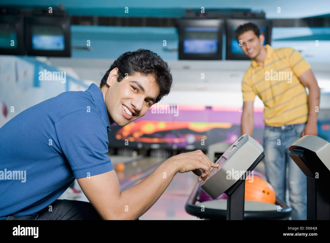 Young man operating the control panel and his friend looking at him in ...