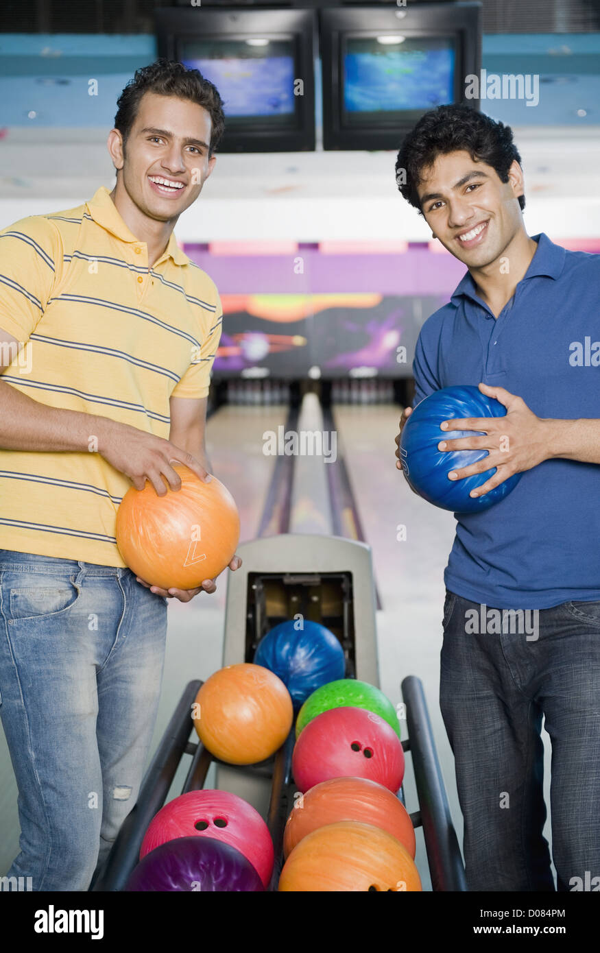 Two young men holding bowling balls in a bowling alley Stock Photo - Alamy