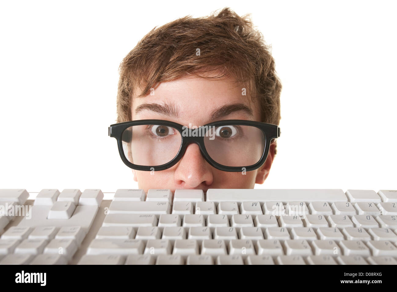 Surprised nerd hides behind a computer keyboard over white background ...