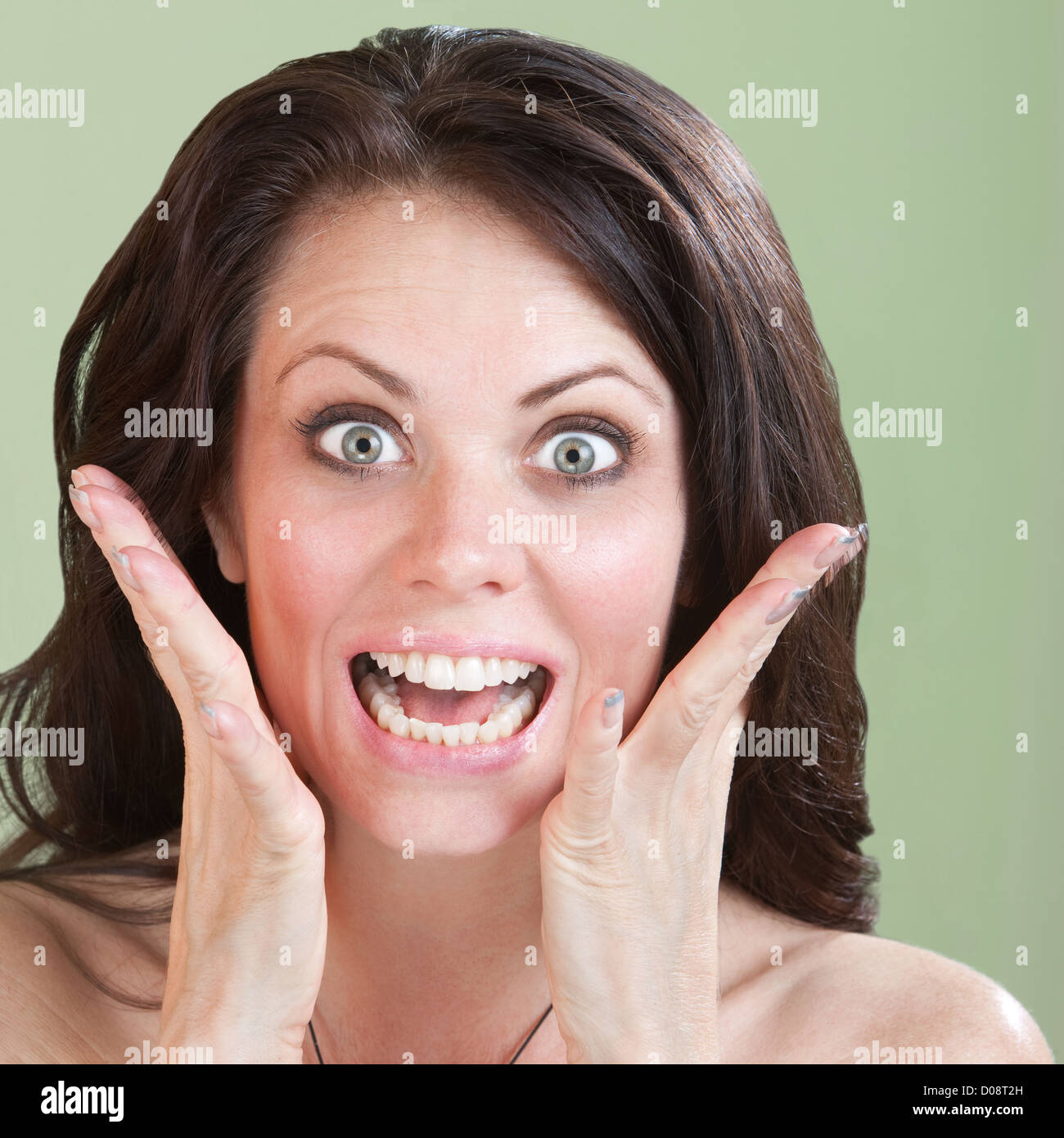 Excited Caucasian woman with raised eyebrows over green background ...