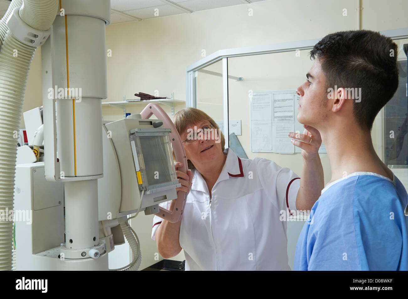 teenage boy patient in X Ray department with nurse and radiographer ...