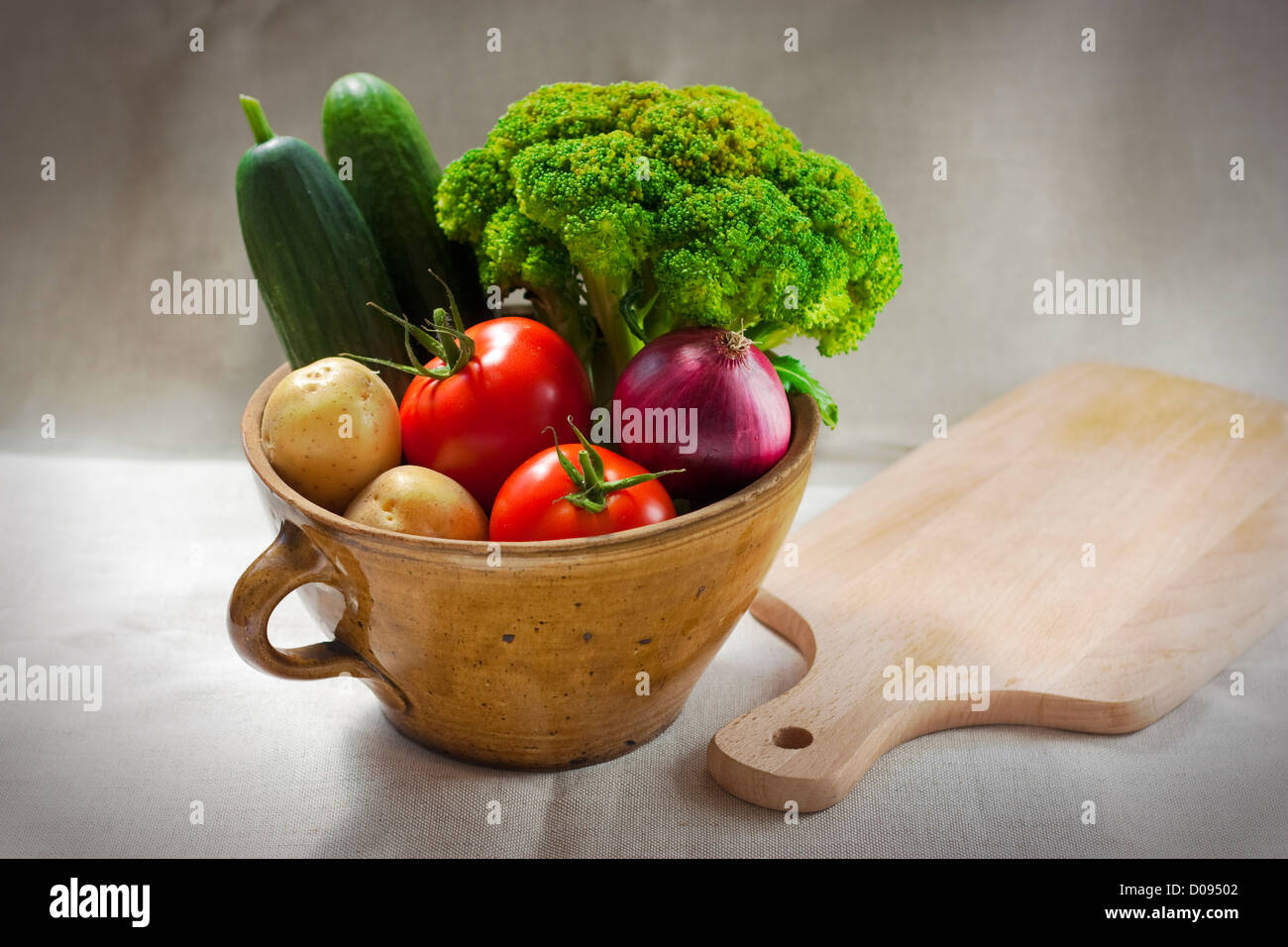 Still life with the clay pot full of vegetables and the breadboard on ...
