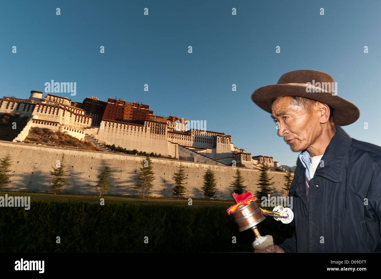 Tibetan Buddhist pilgrim carrying prayer wheel walks around Portala ...