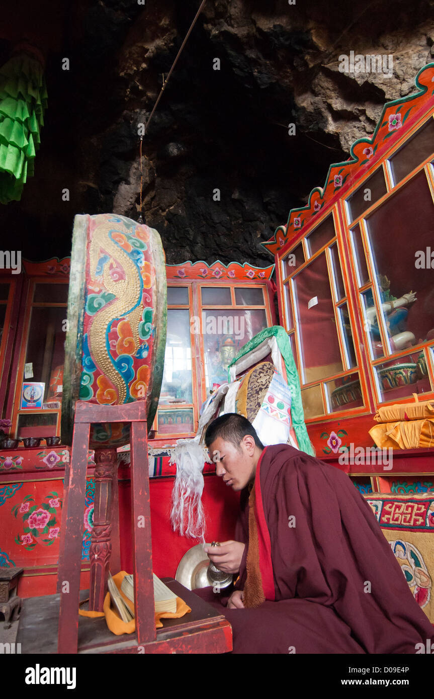 Young Buddhist monk rings bell as he maintains prayer vigil in chapel ...