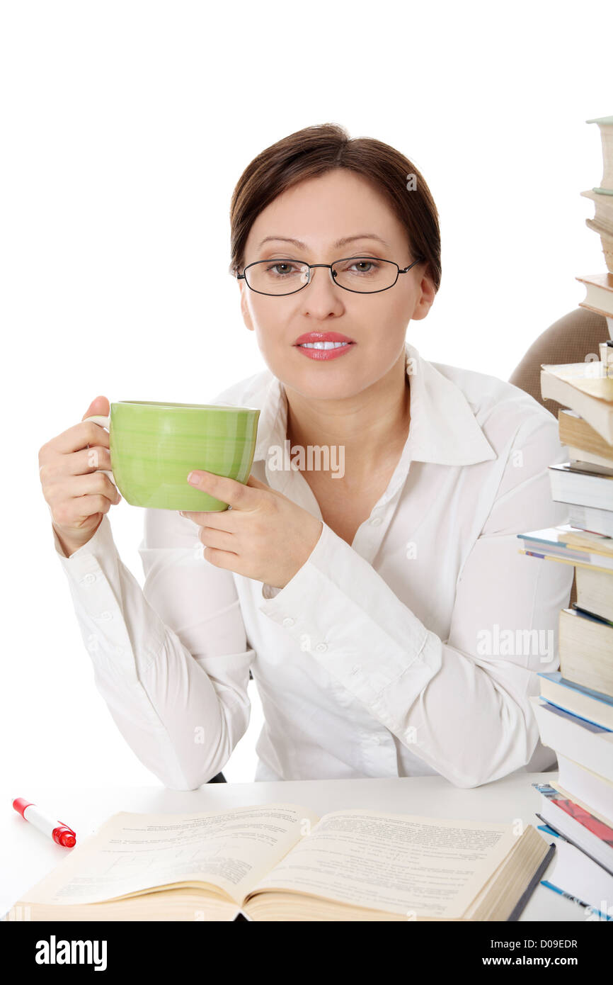Mature student woman at the desk drinking something hot while learning ...