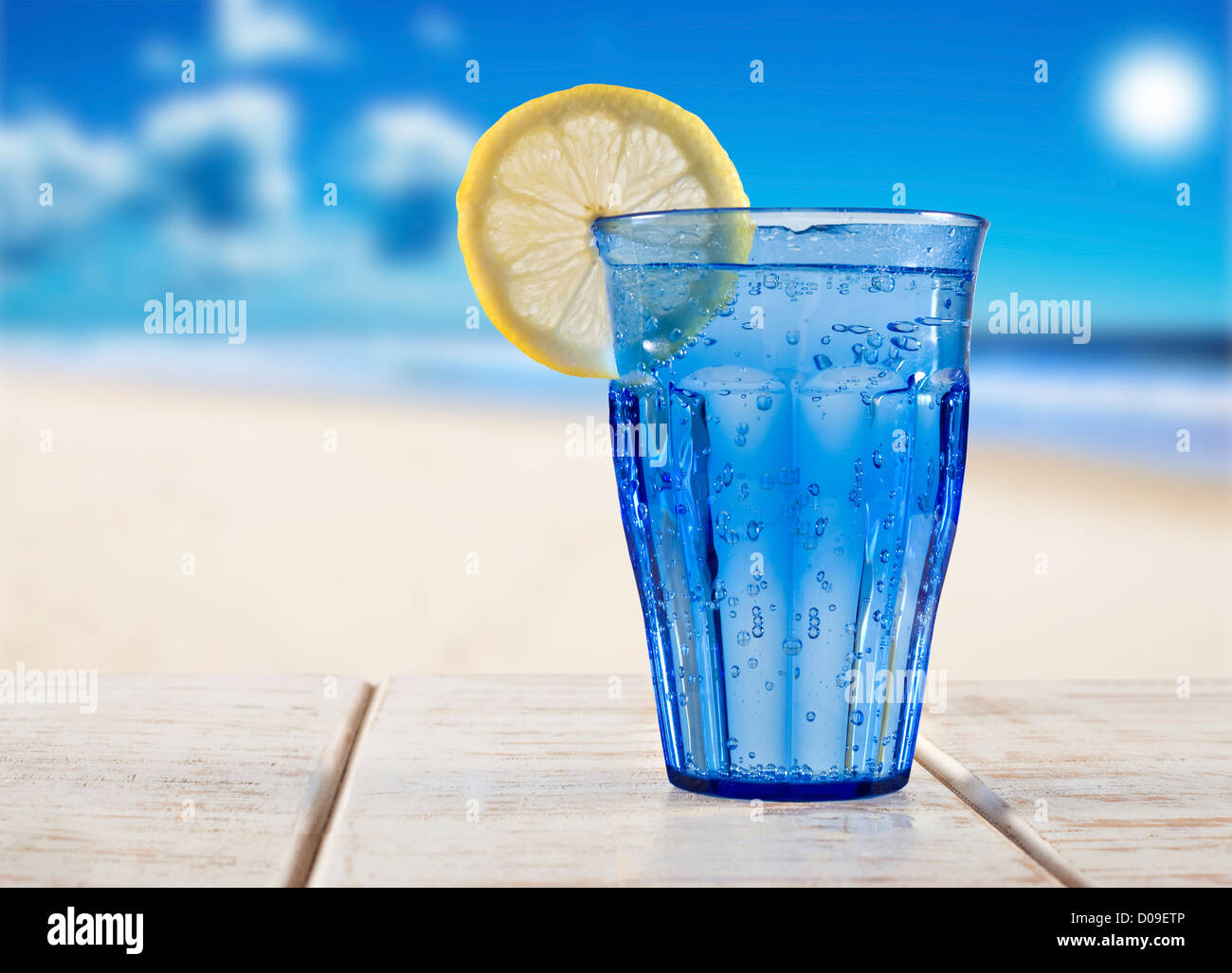 a Blue glass with sparkling water and lemon on a wooden deck ...
