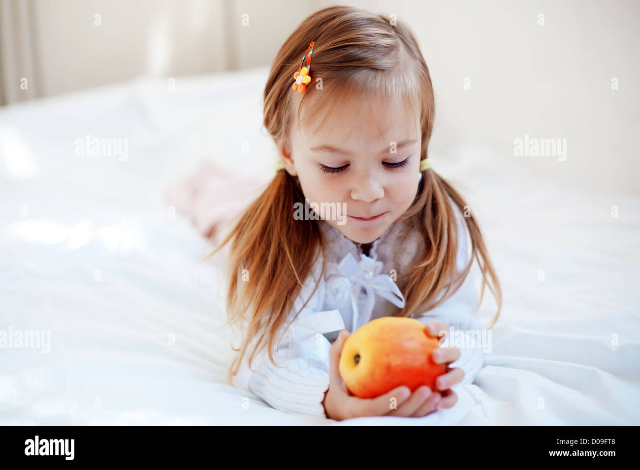 Casual of cute child with apple in bed Stock Photo - Alamy