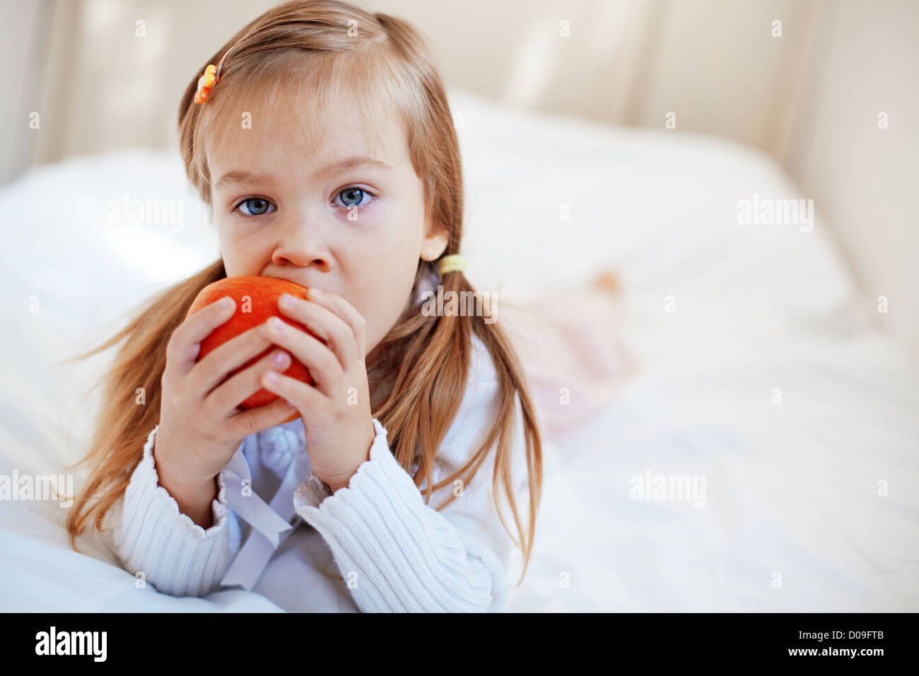 Casual of cute child with apple in bed Stock Photo - Alamy
