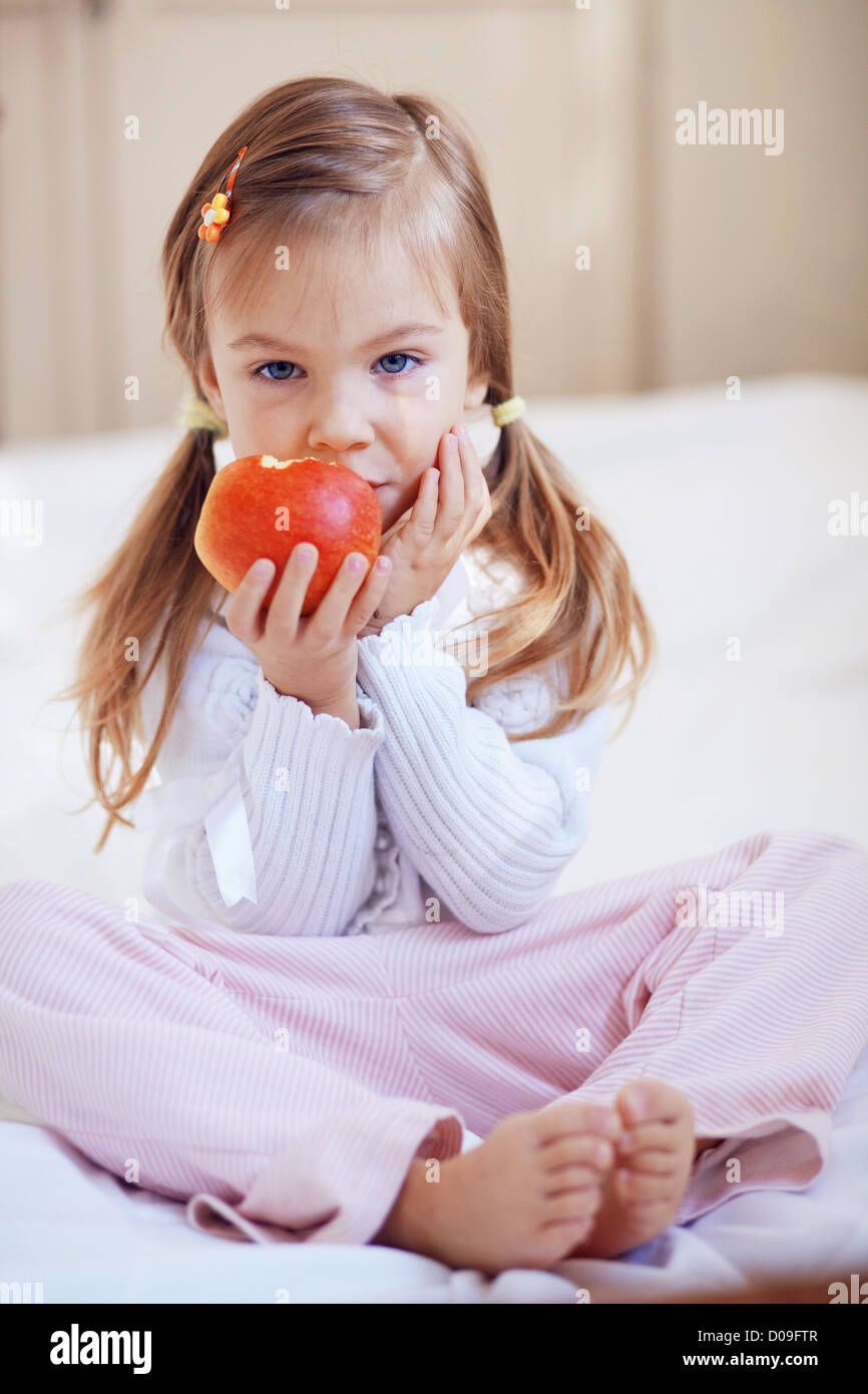 Casual of cute child with apple in bed Stock Photo - Alamy