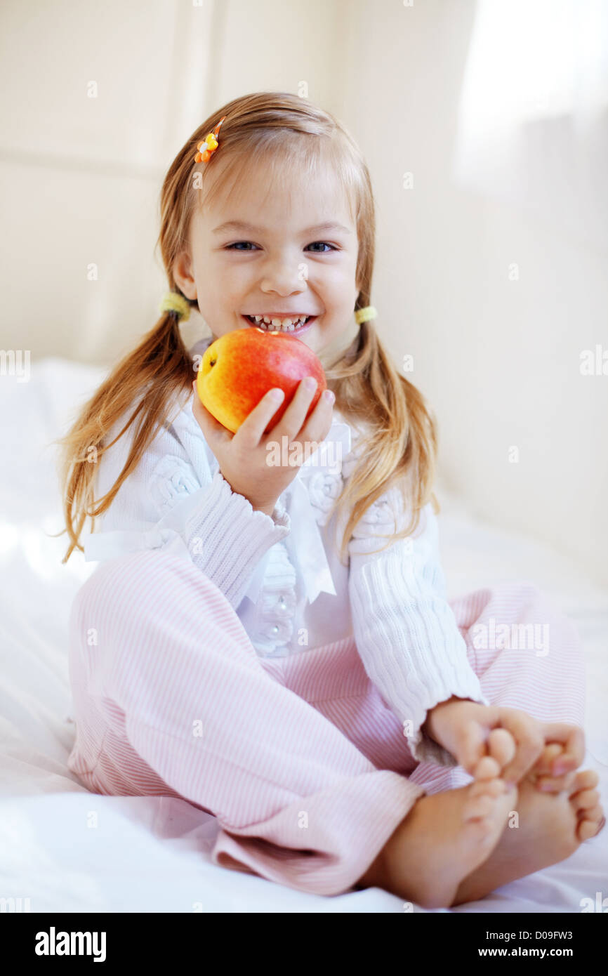 Casual of cute child with apple in bed Stock Photo - Alamy