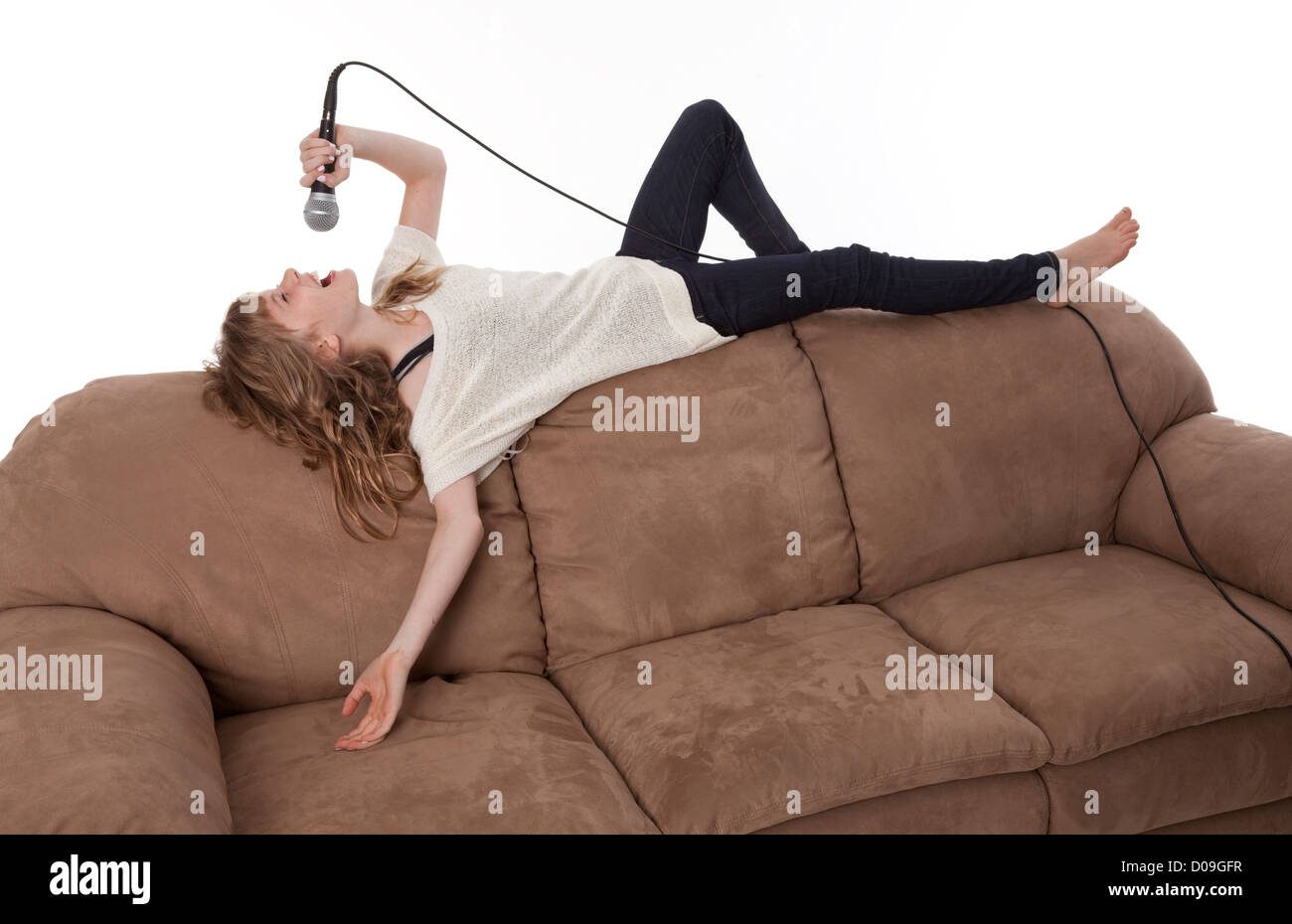 Young girl lying on couch singing into microphone Stock Photo - Alamy