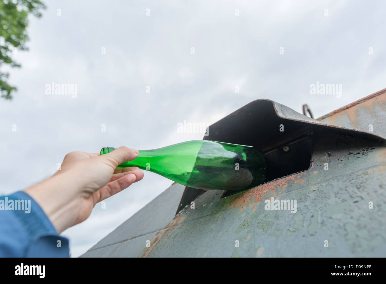 Person throwing a green bottle in a container Stock Photo - Alamy