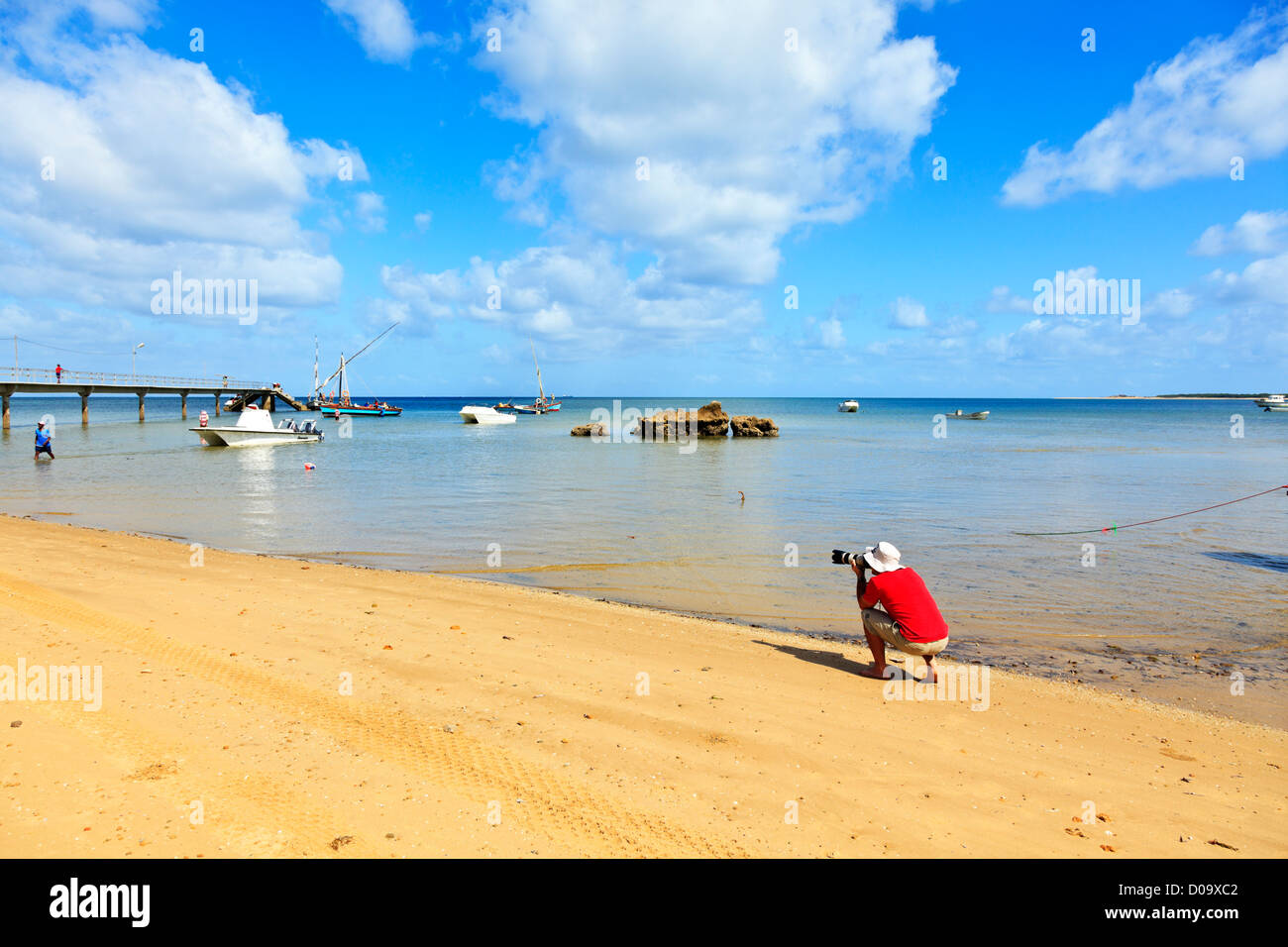 A photographer on holiday takes photographs of a beach scene on the ...