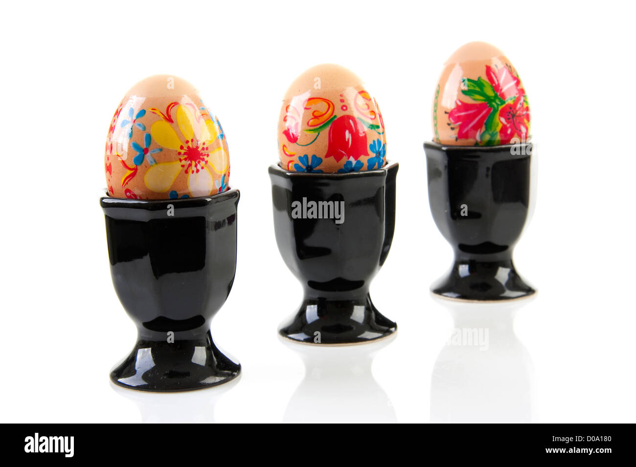 Three decorated chicken eggs in black holder over white background ...
