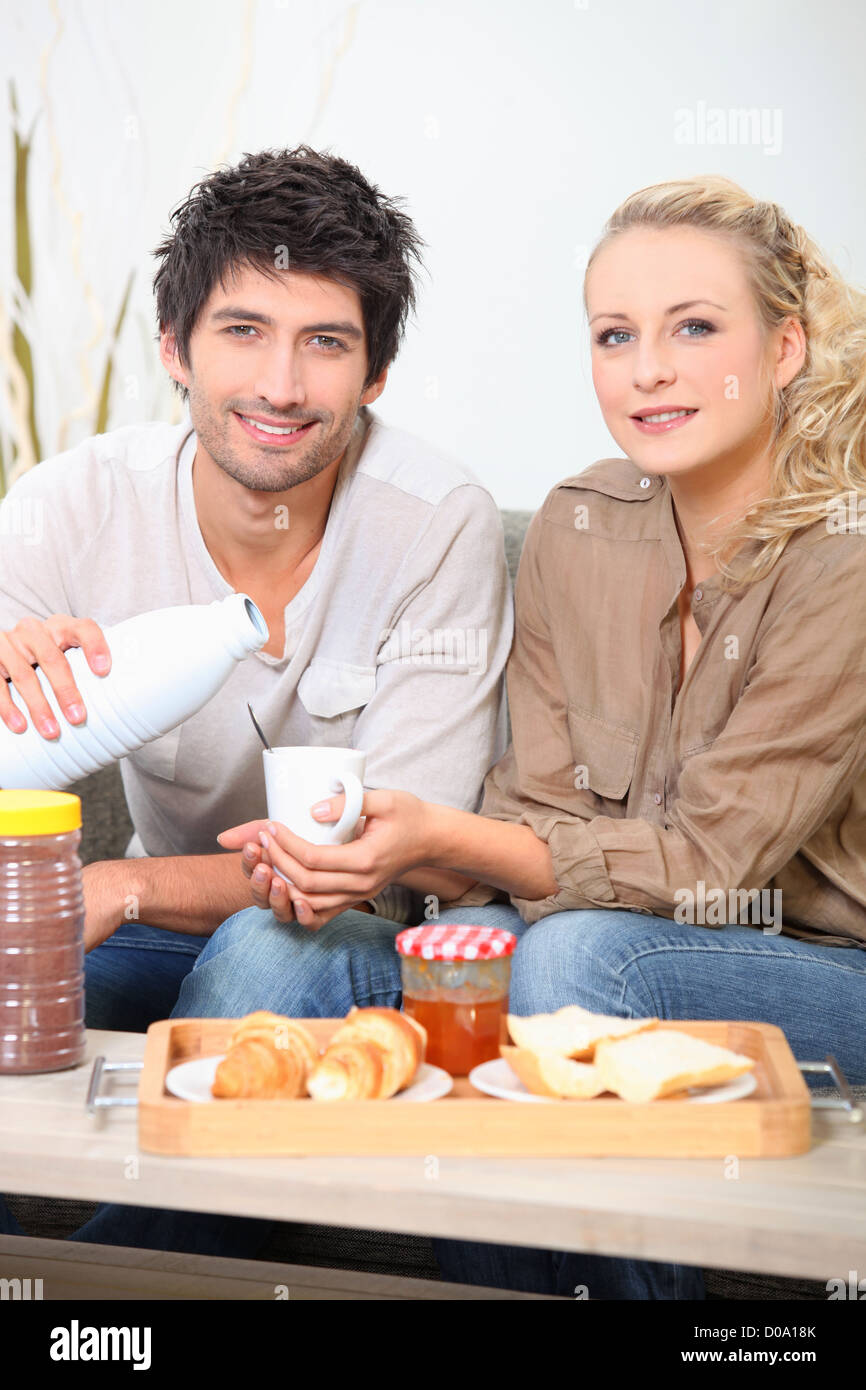 Couple eating breakfast on a sofa Stock Photo - Alamy