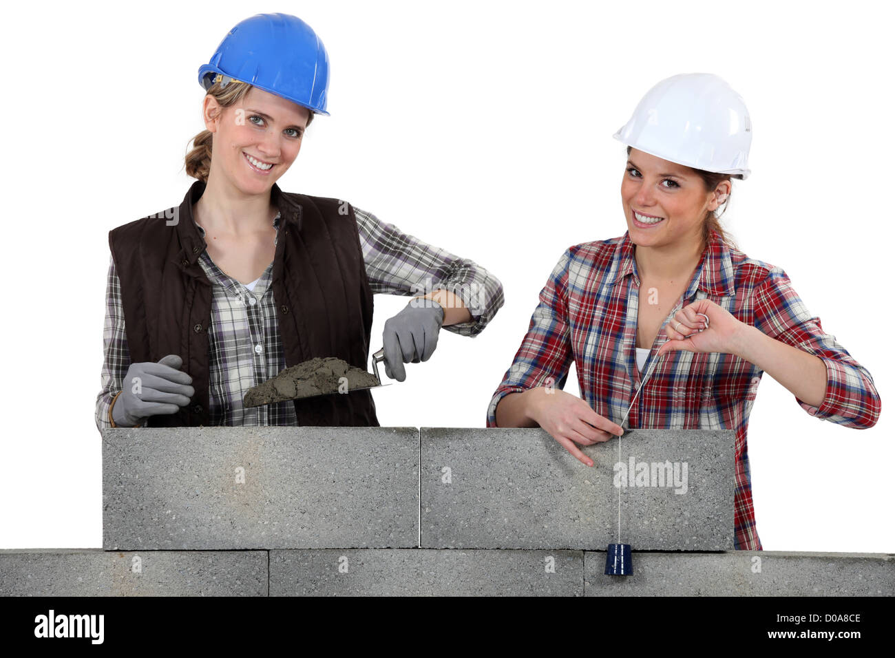 Two women building wall together Stock Photo - Alamy