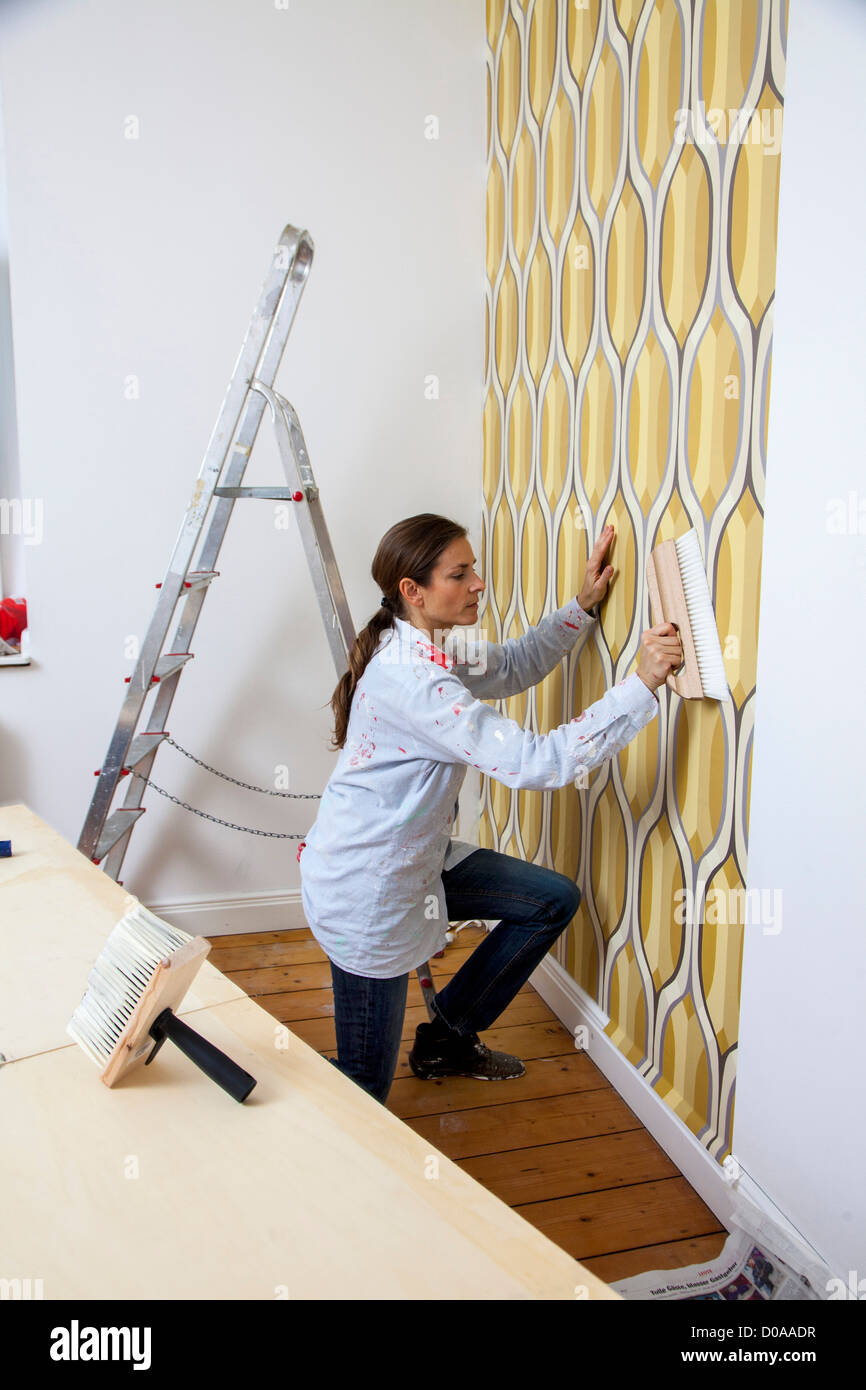 Young wife is renovating her home. Paperhanging, new wallpaper. Do it ...