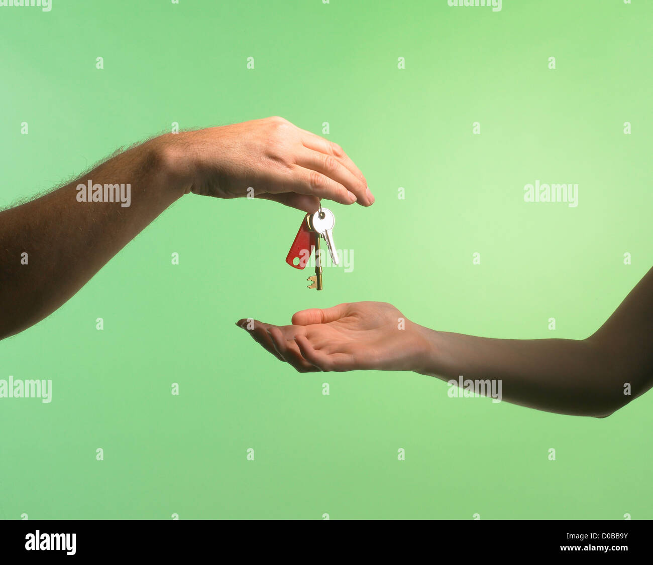 Man handing over house keys to a woman on a green background Stock ...