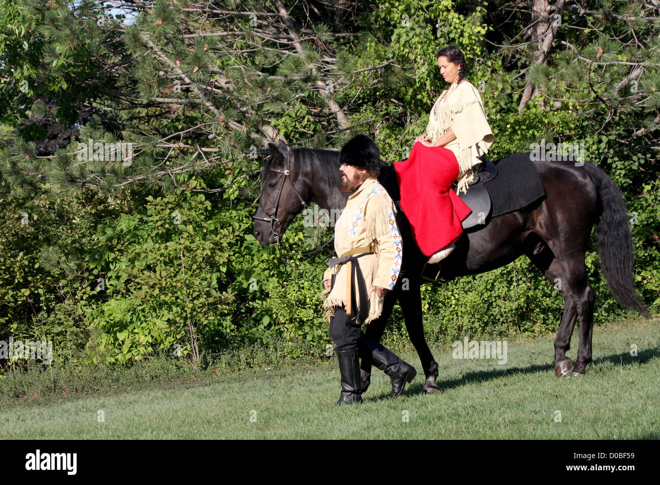 A Native American Indian woman riding a black horse with a pioneer ...