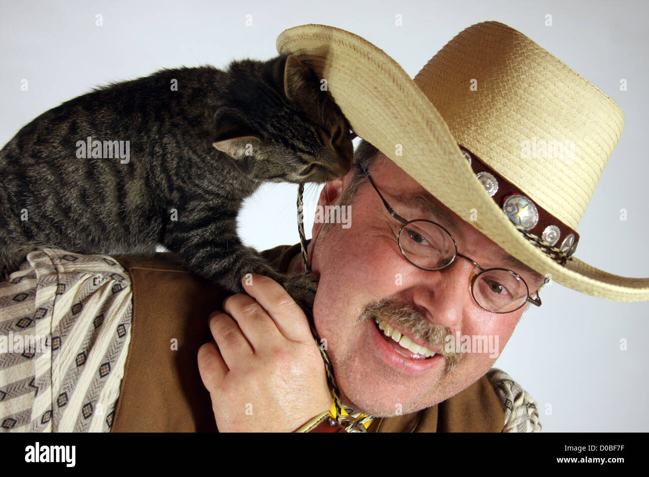 A cat being playful with a cowboy chewing on his hat string Stock Photo ...