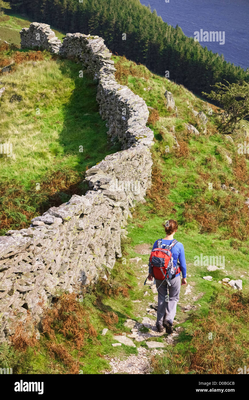 A female hiker walking down towards The Rigg at Haweswater in the Lake ...