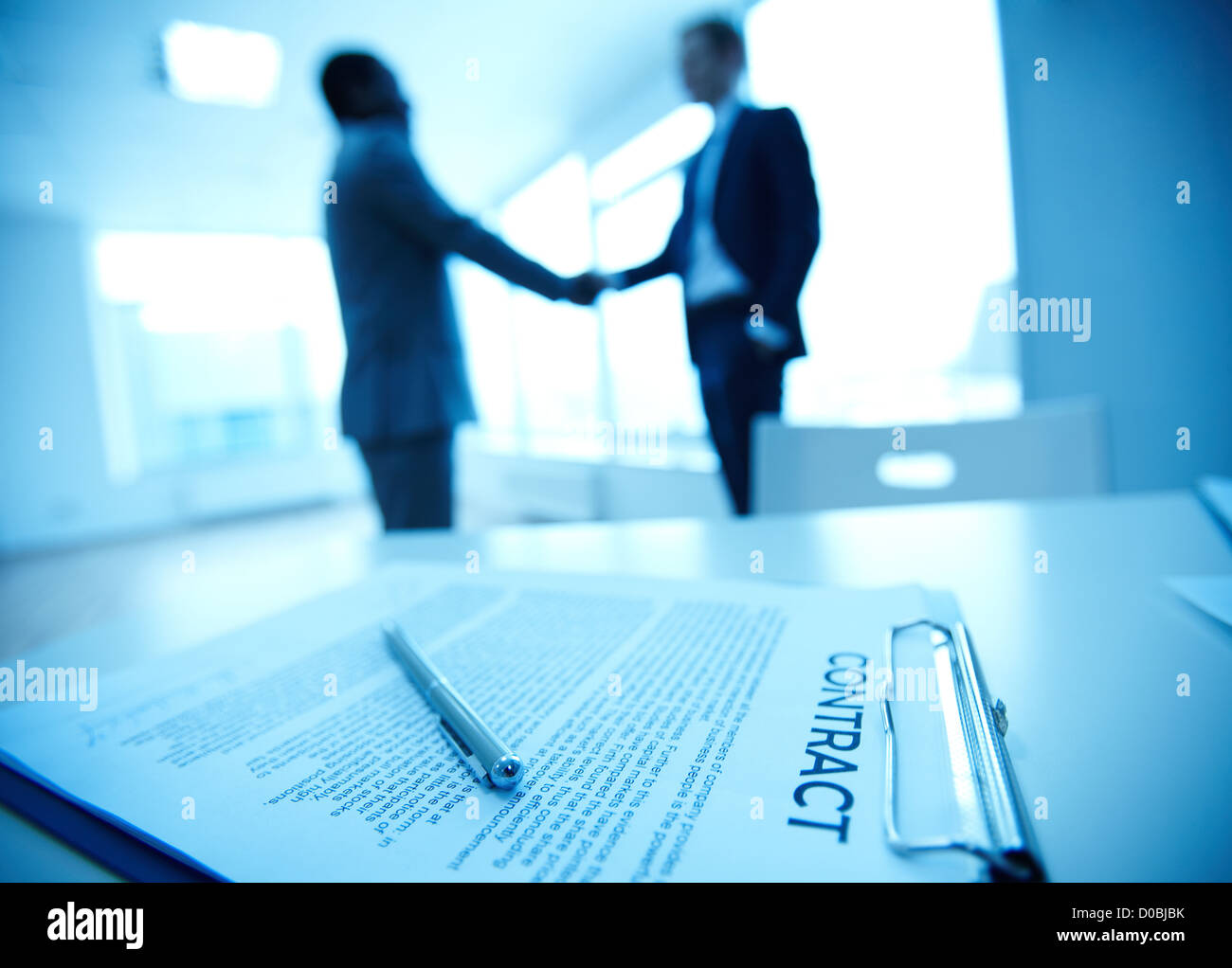 Image of business contract on background of two employees handshaking ...