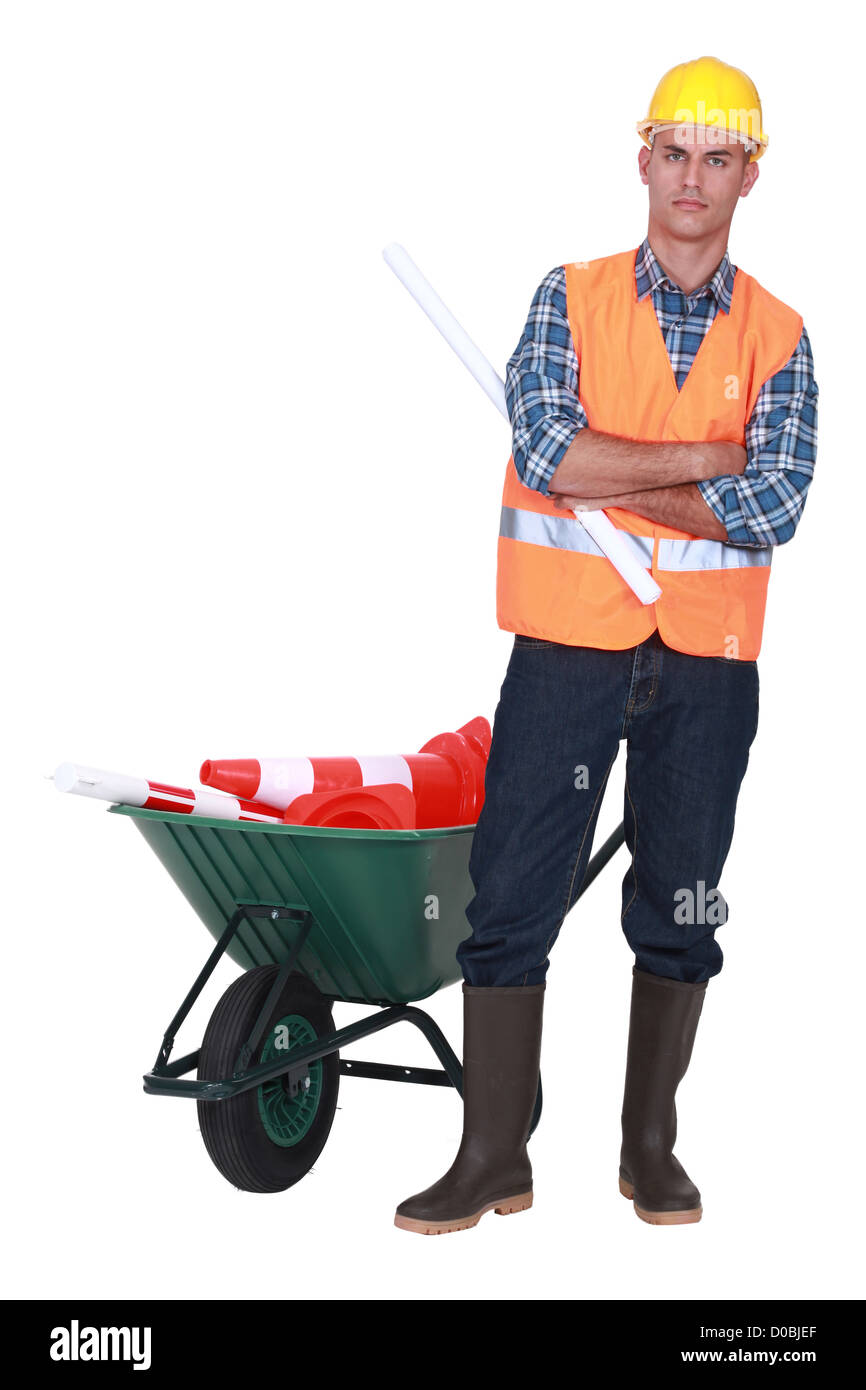 Angry tradesman standing in front of a wheelbarrow Stock Photo - Alamy