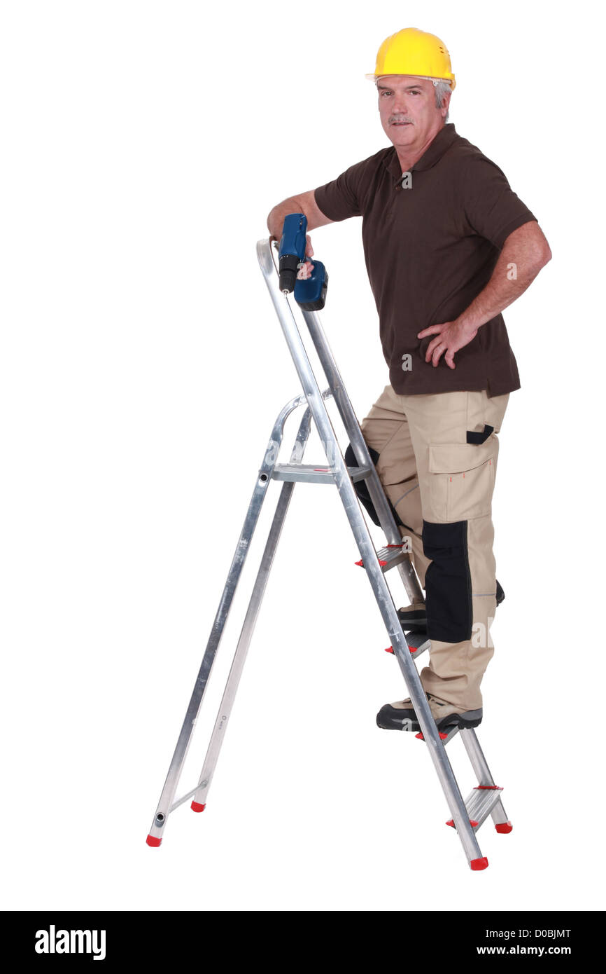 Mature handyman with drill climbing up ladder Stock Photo - Alamy