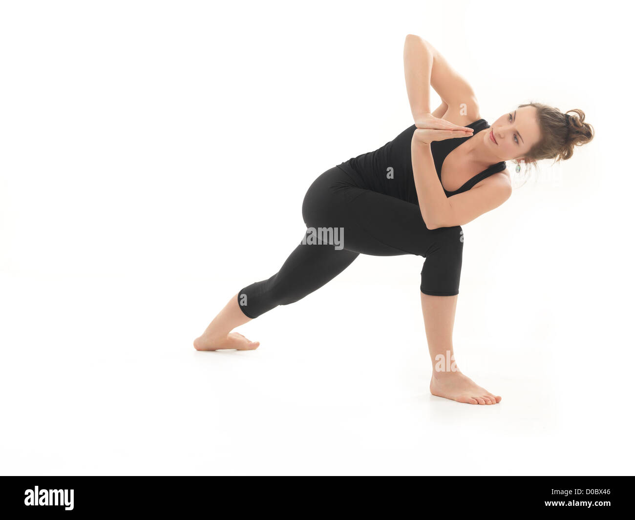 young blonde girl in twisted yoga posture, dressed in black on white ...