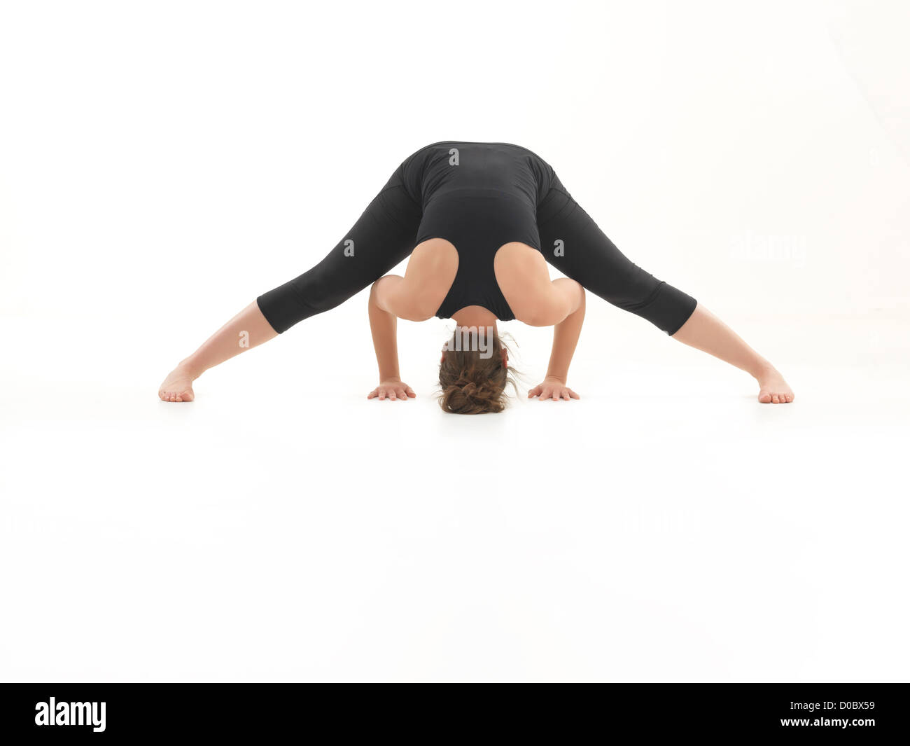 young blonde woman demonstrating yoga pose, bend forward, with face ...