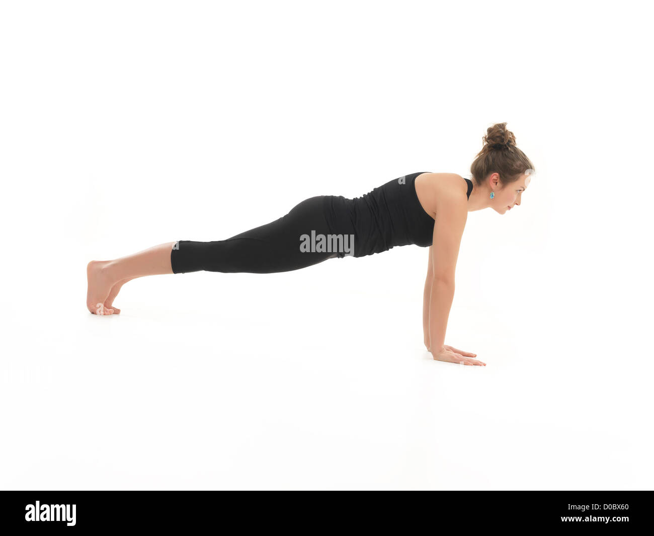 full side view of young woman demonstrating balancing yoga pose ...
