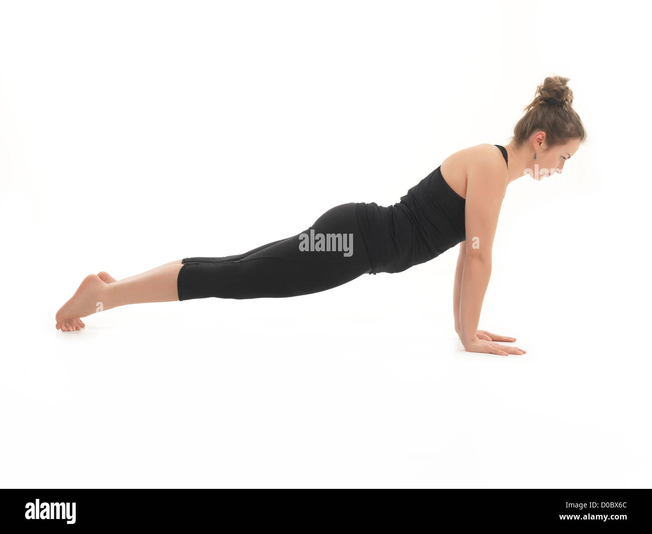 side view of a ypung woman in yoga posture, dressed in black on white ...