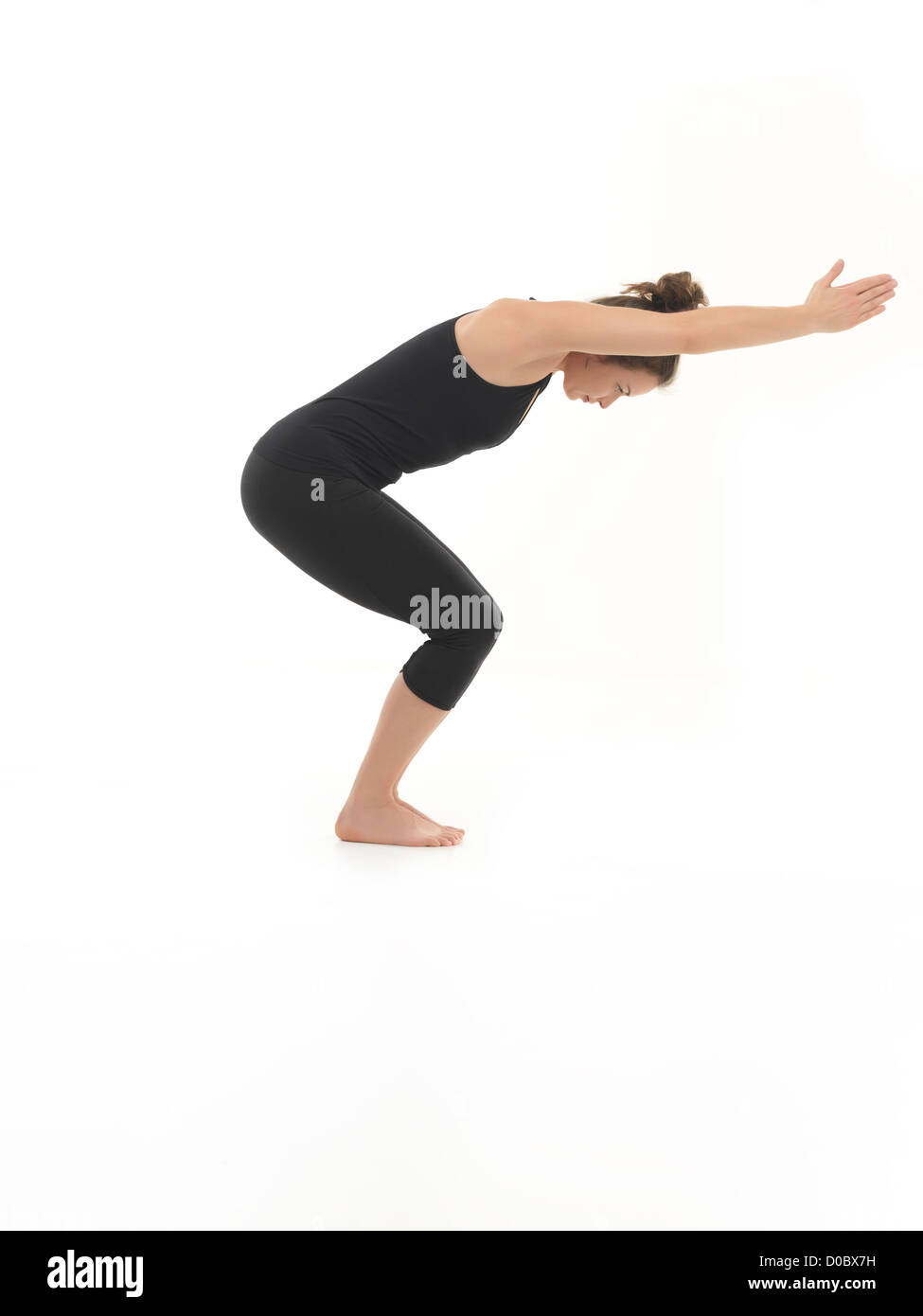 side view of attractive young woman demonstrating yoga pose, dressed in ...