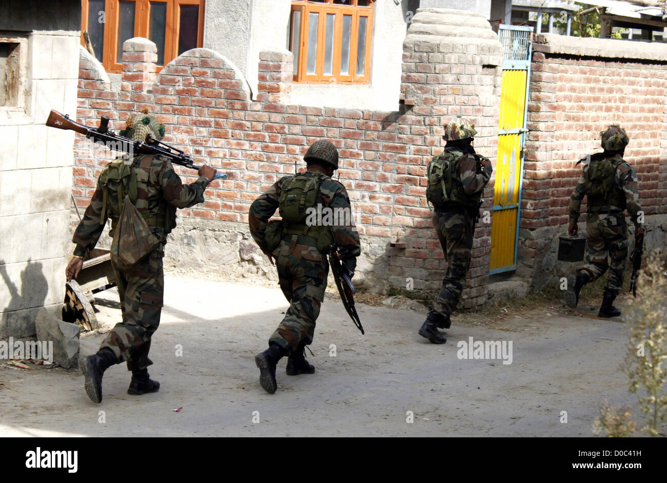 Indian Army soldiers take cover behind a wall as they try to storm a ...