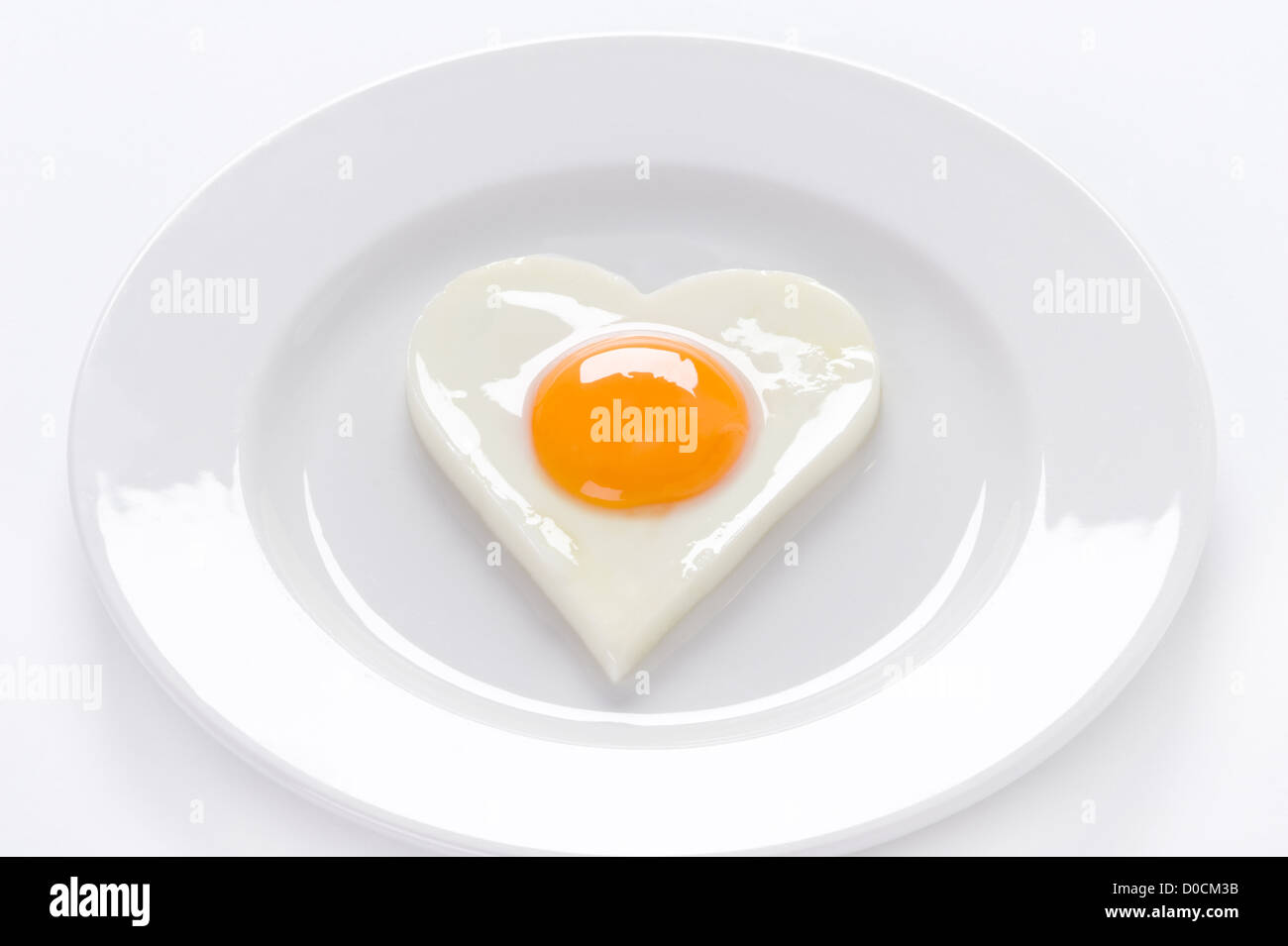 heart shaped cooked egg presented soft 'sunny side up' on a white ...