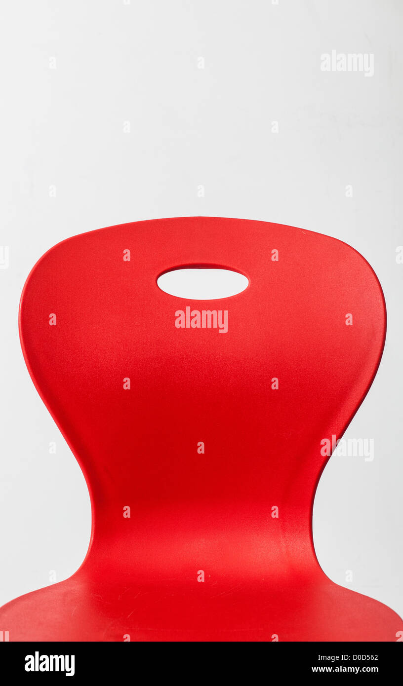 A red plastic office chair against a white wall Stock Photo - Alamy