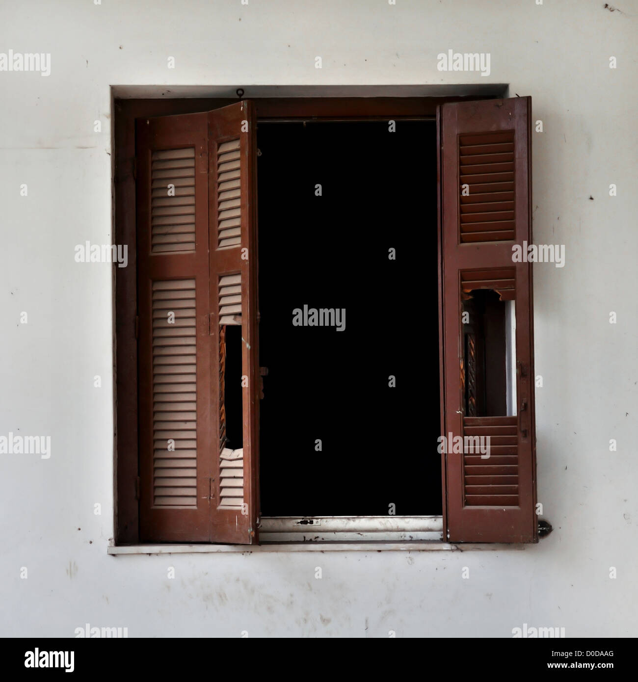 Wooden window shutter cracked open and dirty wall of an abandoned house ...