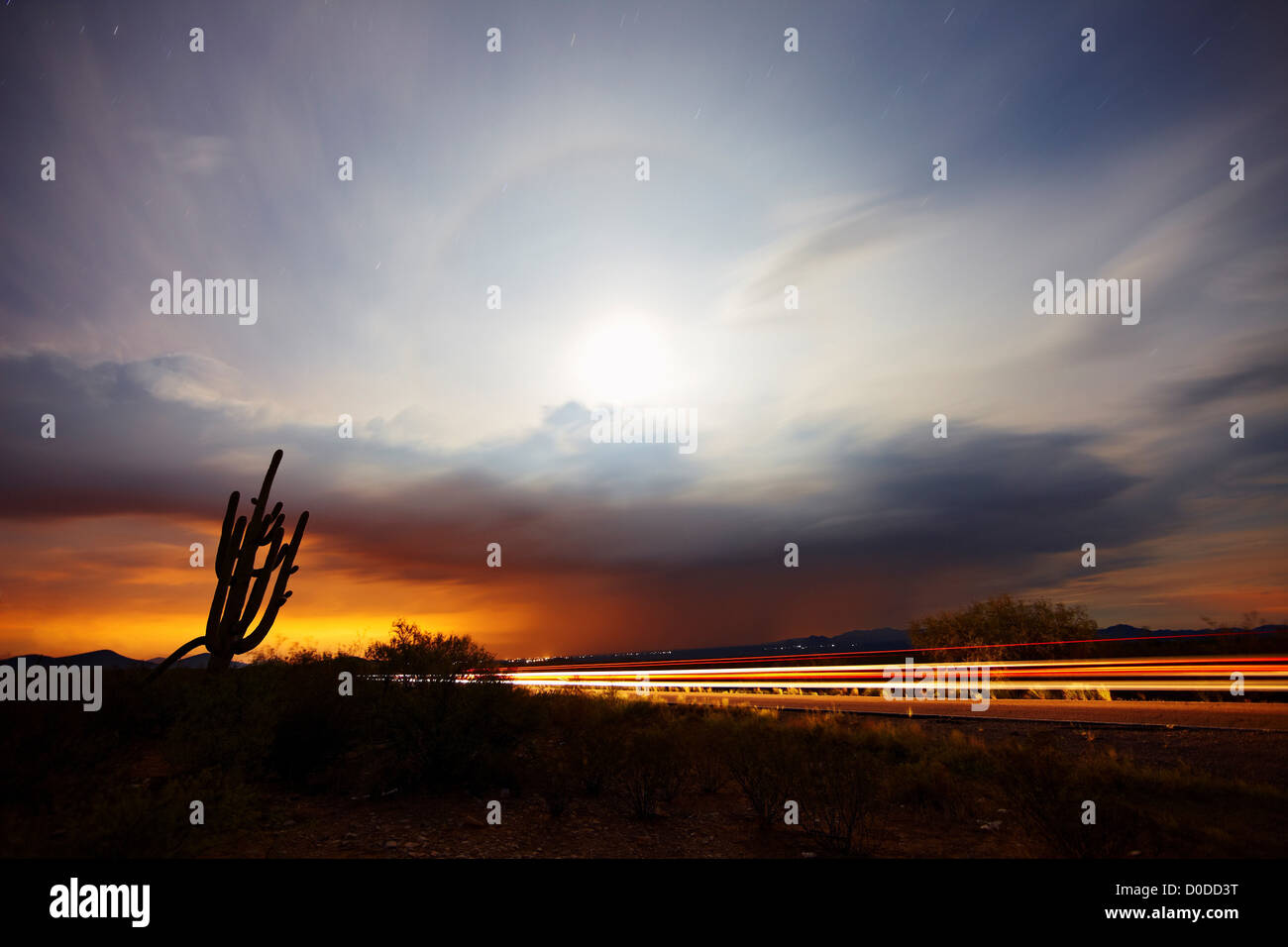 During nighttime thunderstorm halo forms around moon as cars drive down ...
