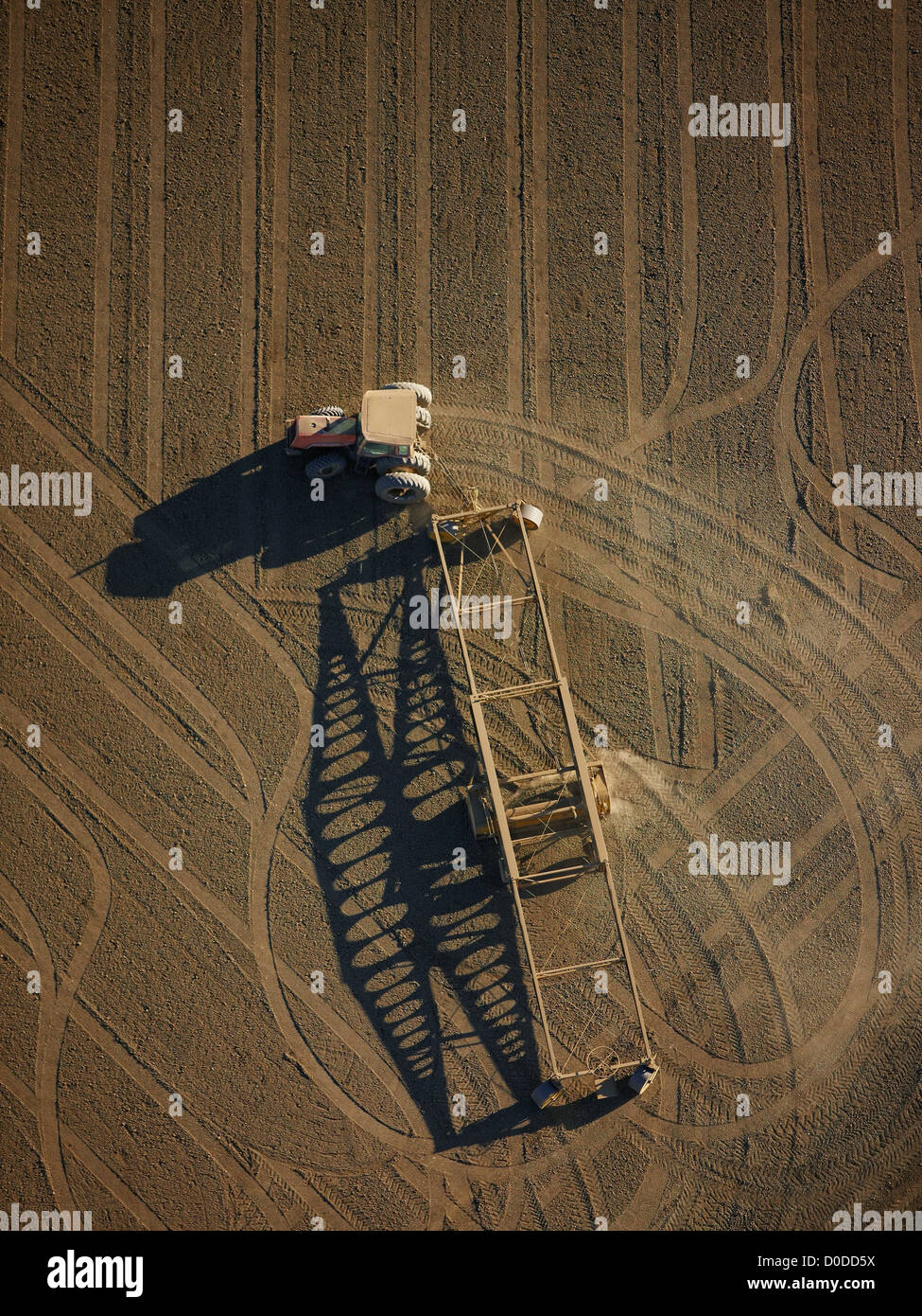 An aerial view of a tractor pulling a planing mechanism to grade an ...