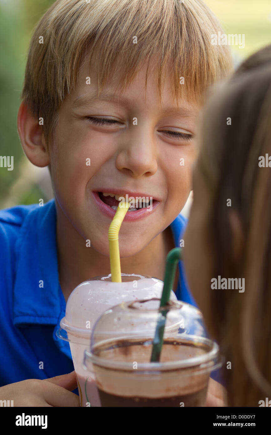 Little brother and sister drinking milkshakes in a cafe outdoors Stock ...