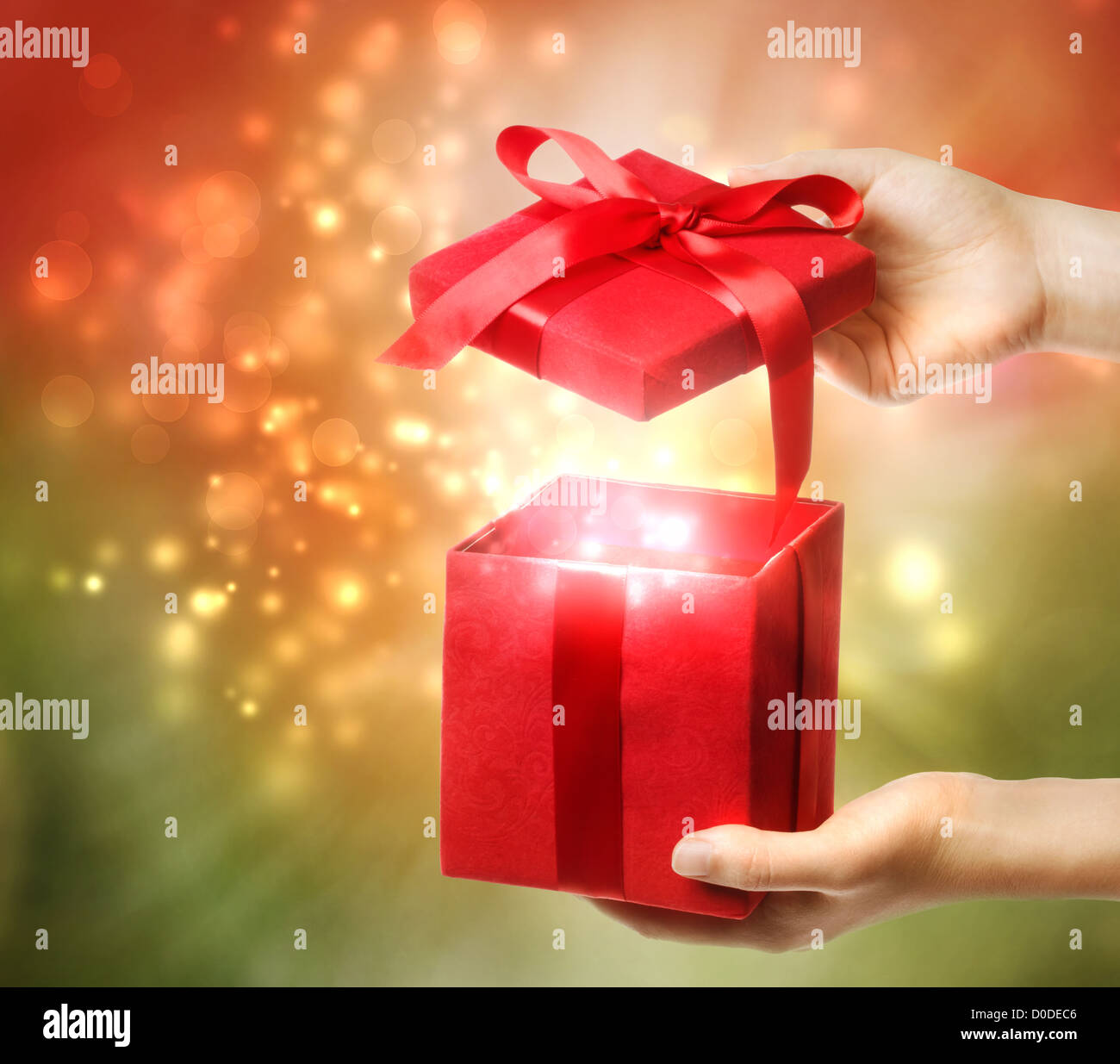 Woman holding a red gift box on a bright holiday lights background ...