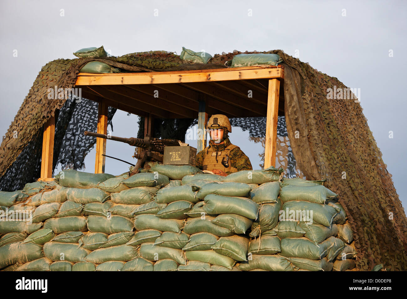A U.S. Marine stands guard at a combat outpost behind a .50 caliber ...