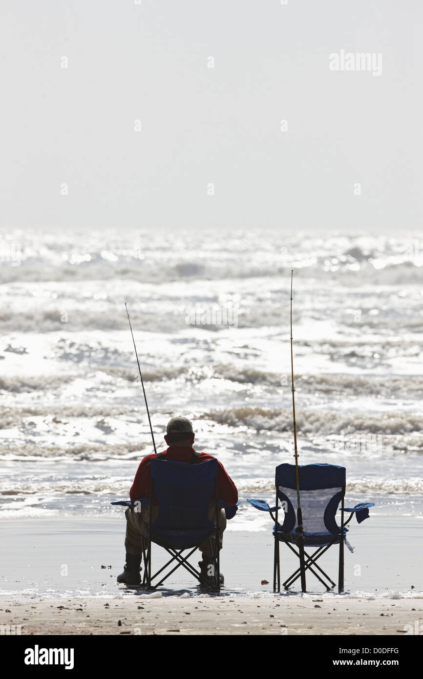 A fisherman waits for a fish to bite his line in the surf, Galveston ...